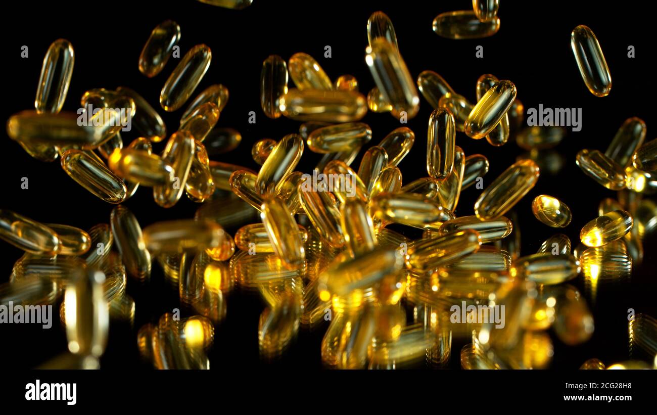 Freeze motion of flying group of fish fat pills on black background ...