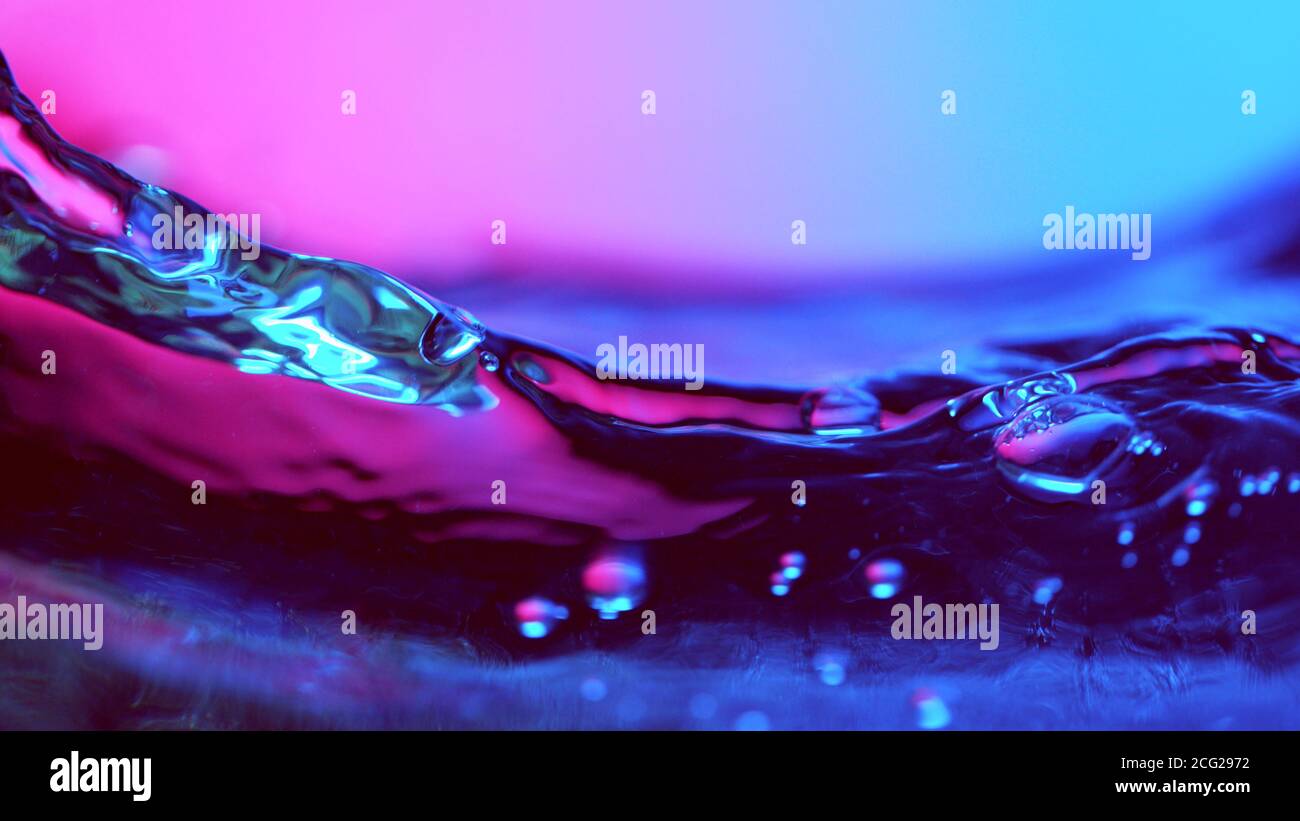 Detail of water waves highlighted by neon lights. Abstract water ...