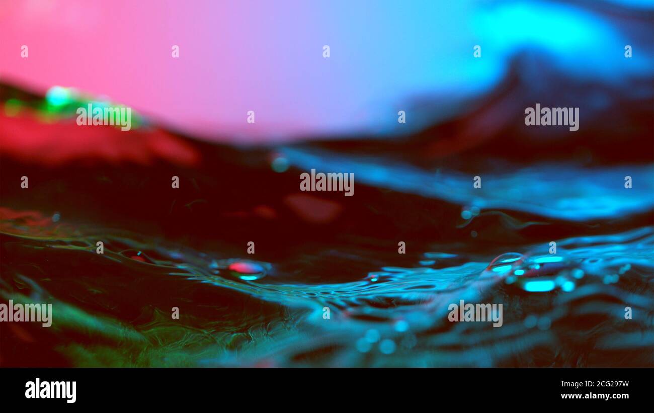 Detail of water waves highlighted by neon lights. Abstract water ...