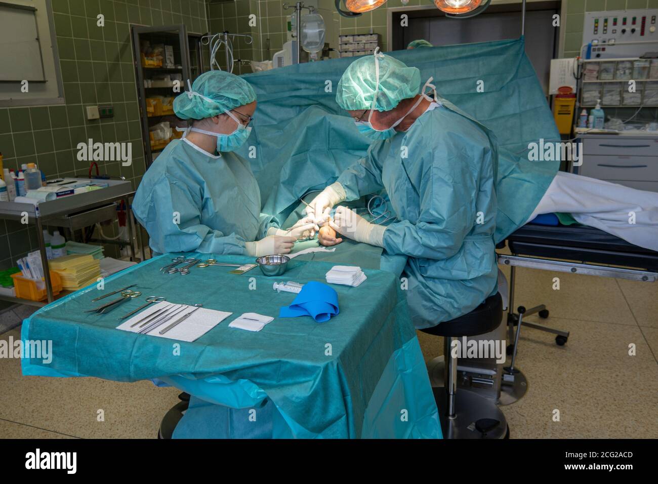 a plastic surgeon performs hand surgery on a patient in an operating ...