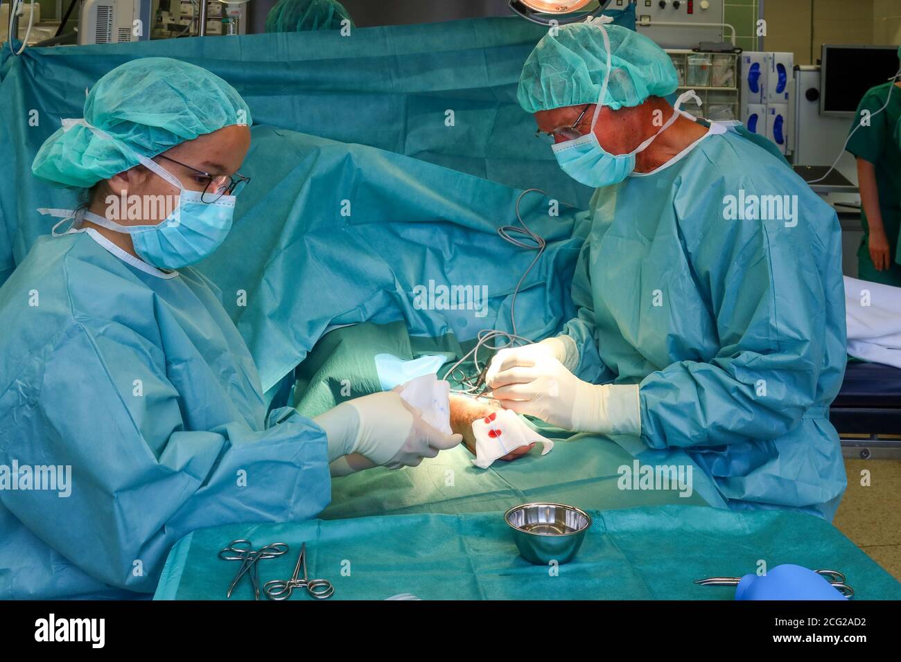 a plastic surgeon performs hand surgery on a patient in an operating ...