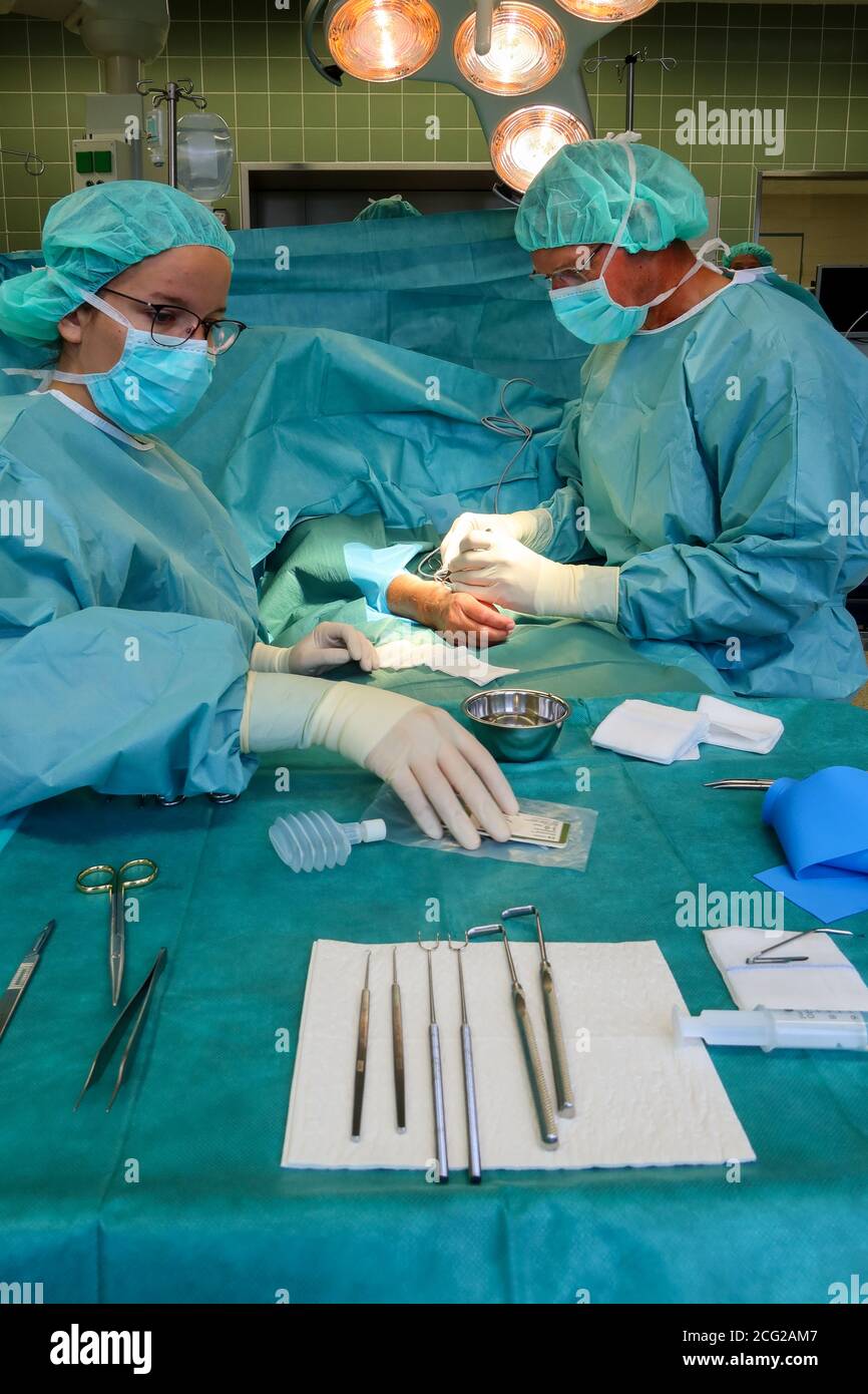 a plastic surgeon performs hand surgery on a patient in an operating ...