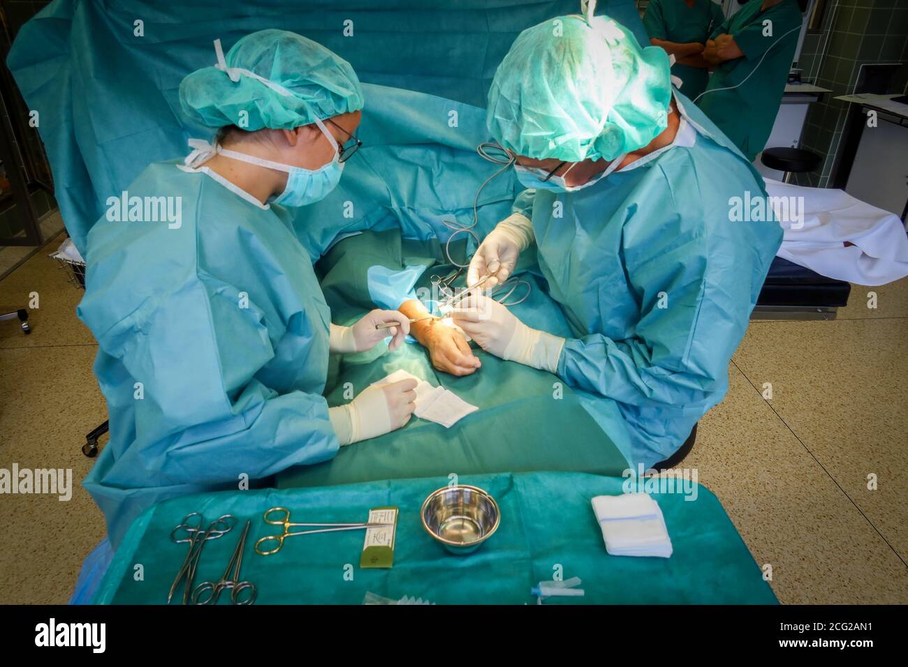 a plastic surgeon performs hand surgery on a patient in an operating ...