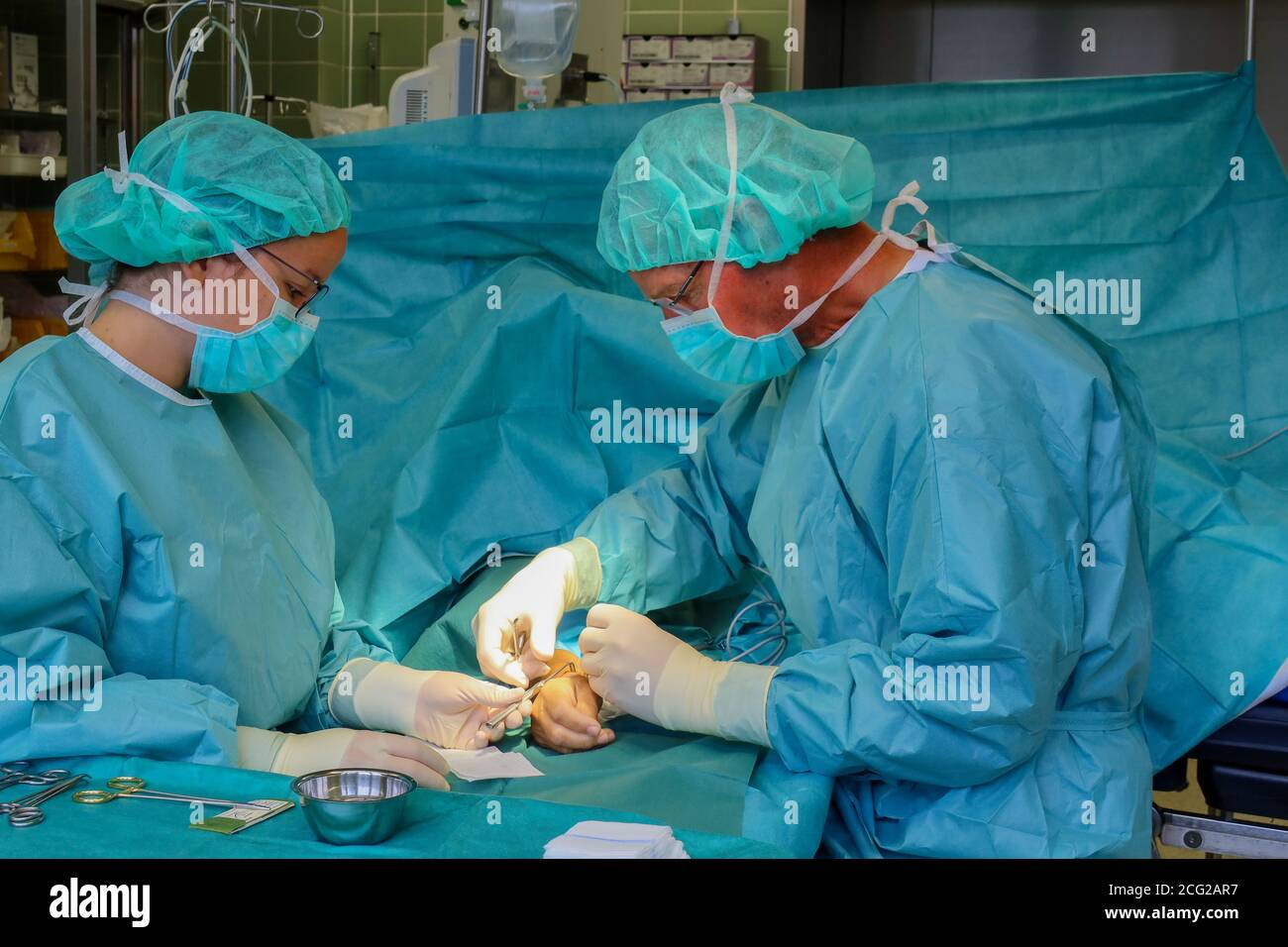 a plastic surgeon performs hand surgery on a patient in an operating ...