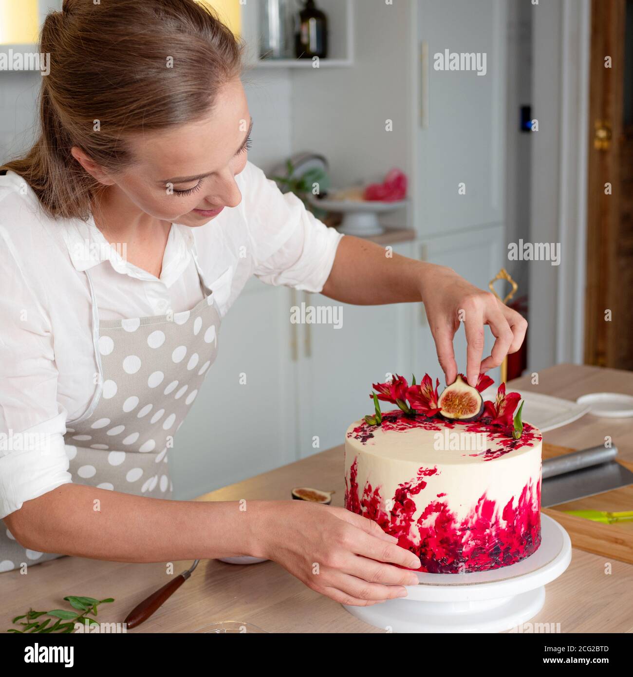 Cooking and decoration of cake with cream. Young woman pastry chef in ...