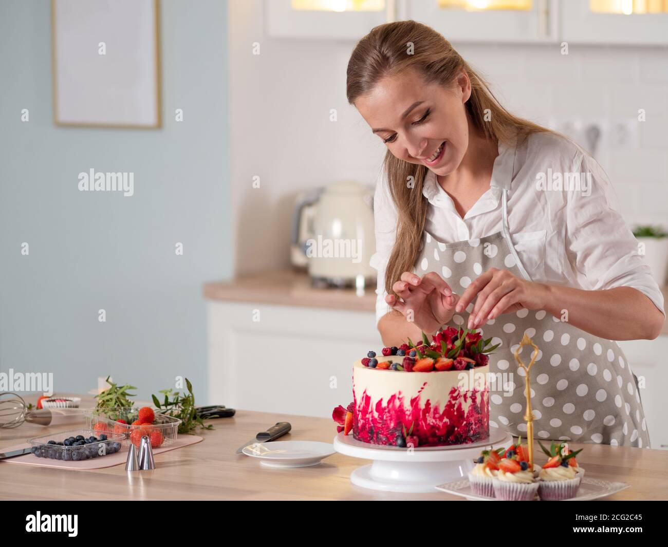 Cooking and decoration of cake with cream. Young woman pastry chef in ...