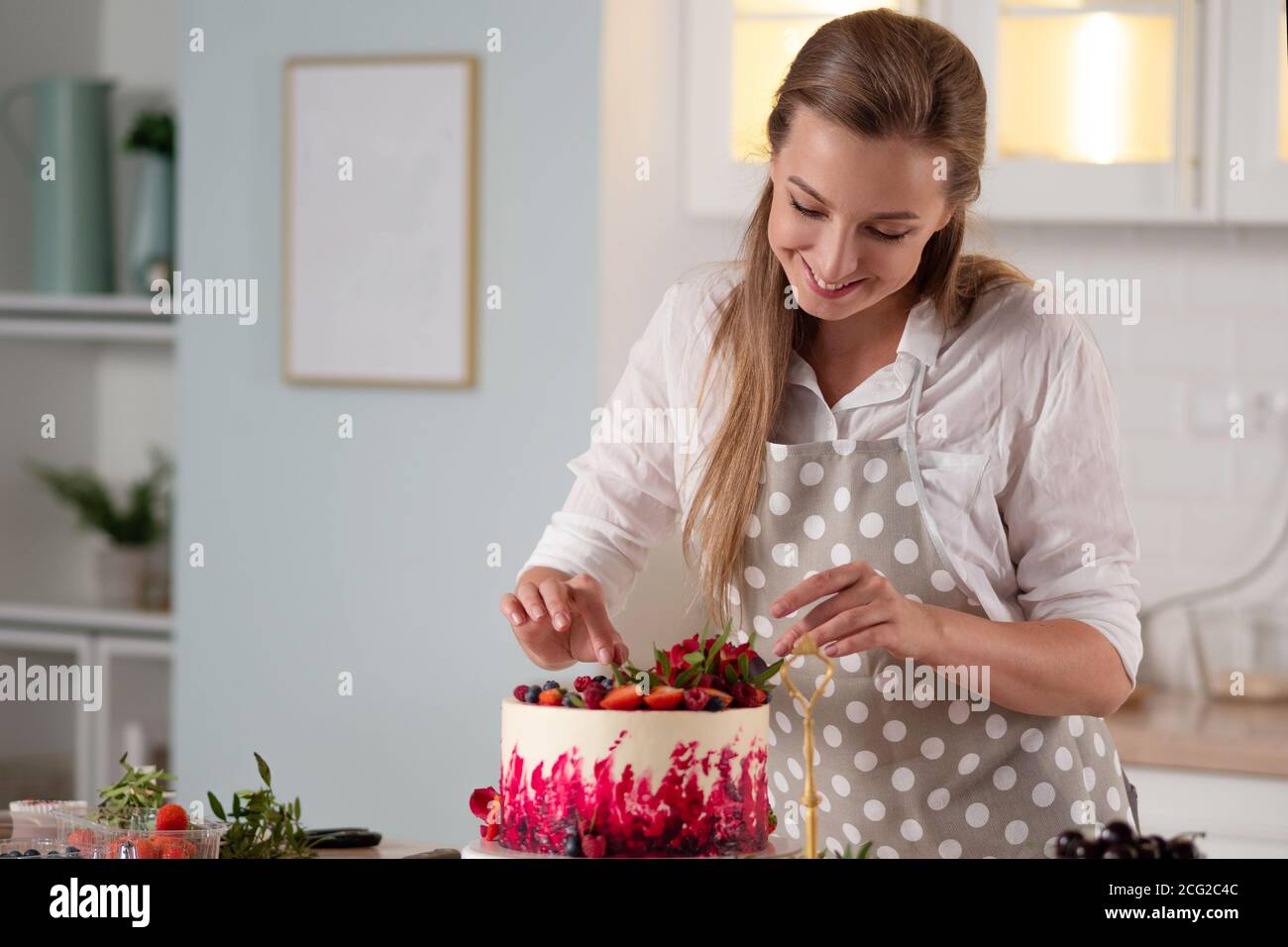 Cooking and decoration of cake with cream. Young woman pastry chef in ...