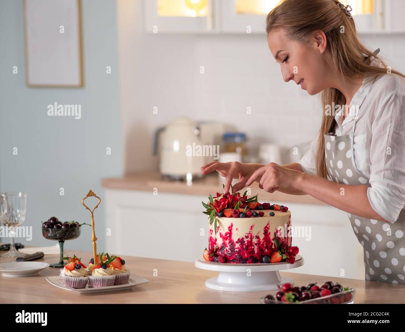 cooking and decoration of cake with cream. Young woman pastry chef in ...