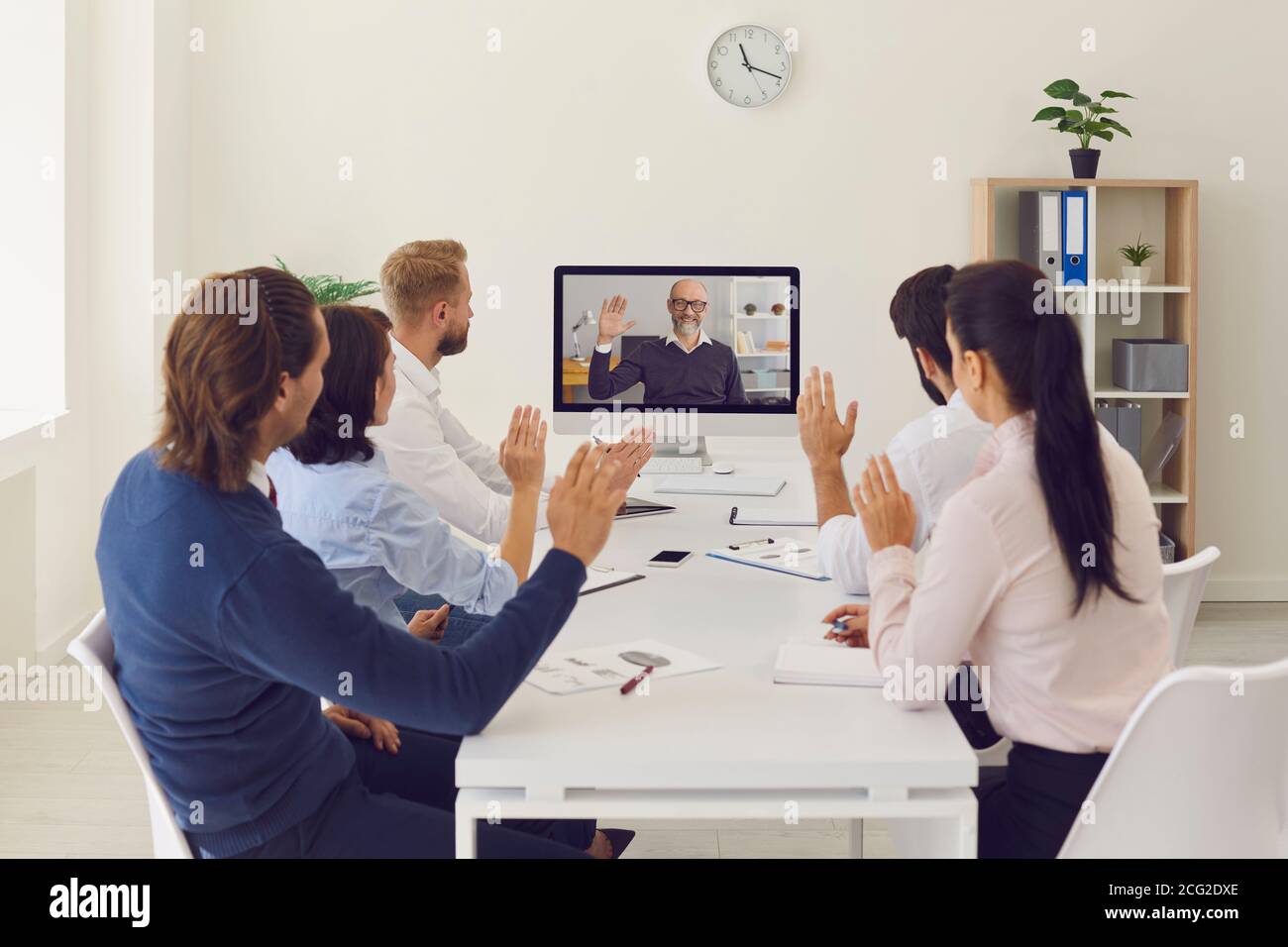 Company workers sitting in office having online meeting with their CEO ...