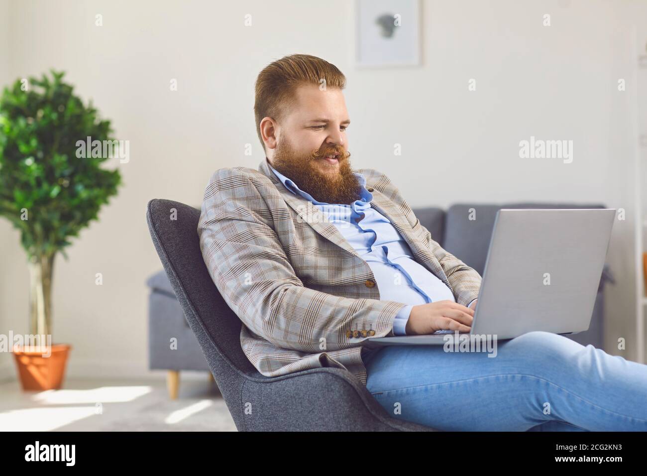Work online at home office. Funny fat man works using a laptop in the ...