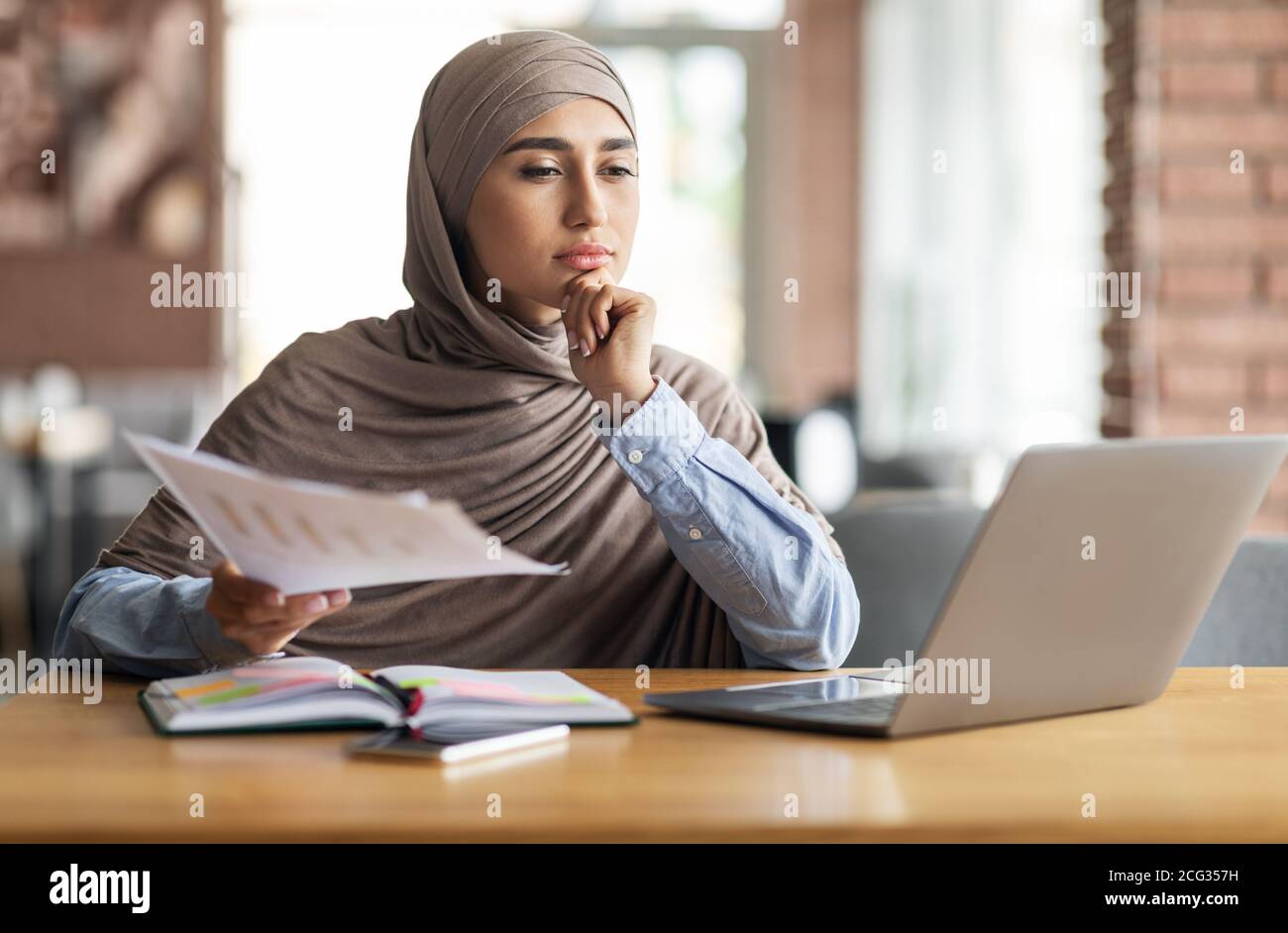 Pensive muslim woman manager working while sitting at cafe Stock Photo ...