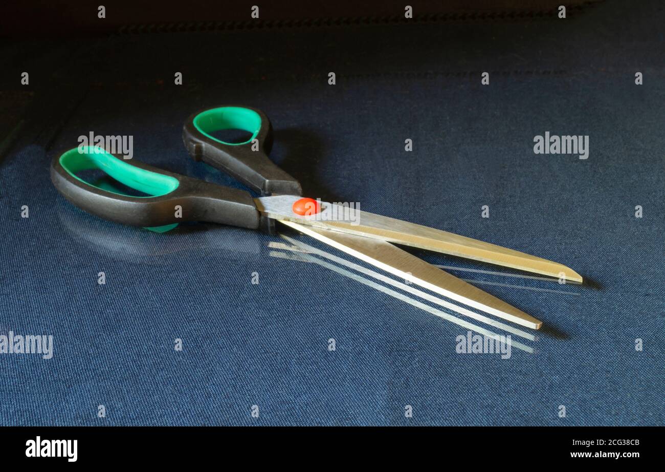 The Scissors on glass table with reflection on black background ...