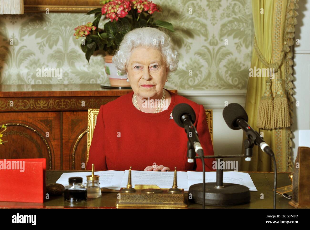 Queen Elizabeth II sits at a desk with microphones in Buckingham Palace ...