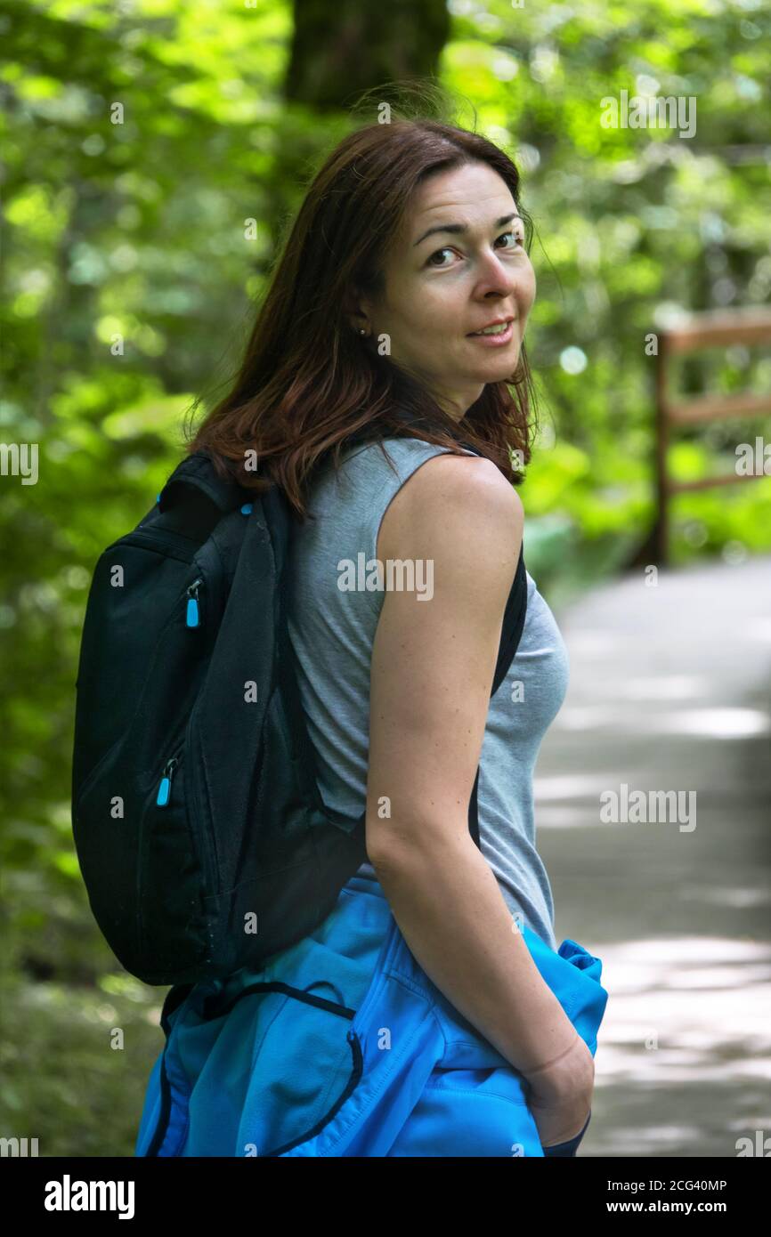 Woman looking back while walking through the forest Stock Photo - Alamy