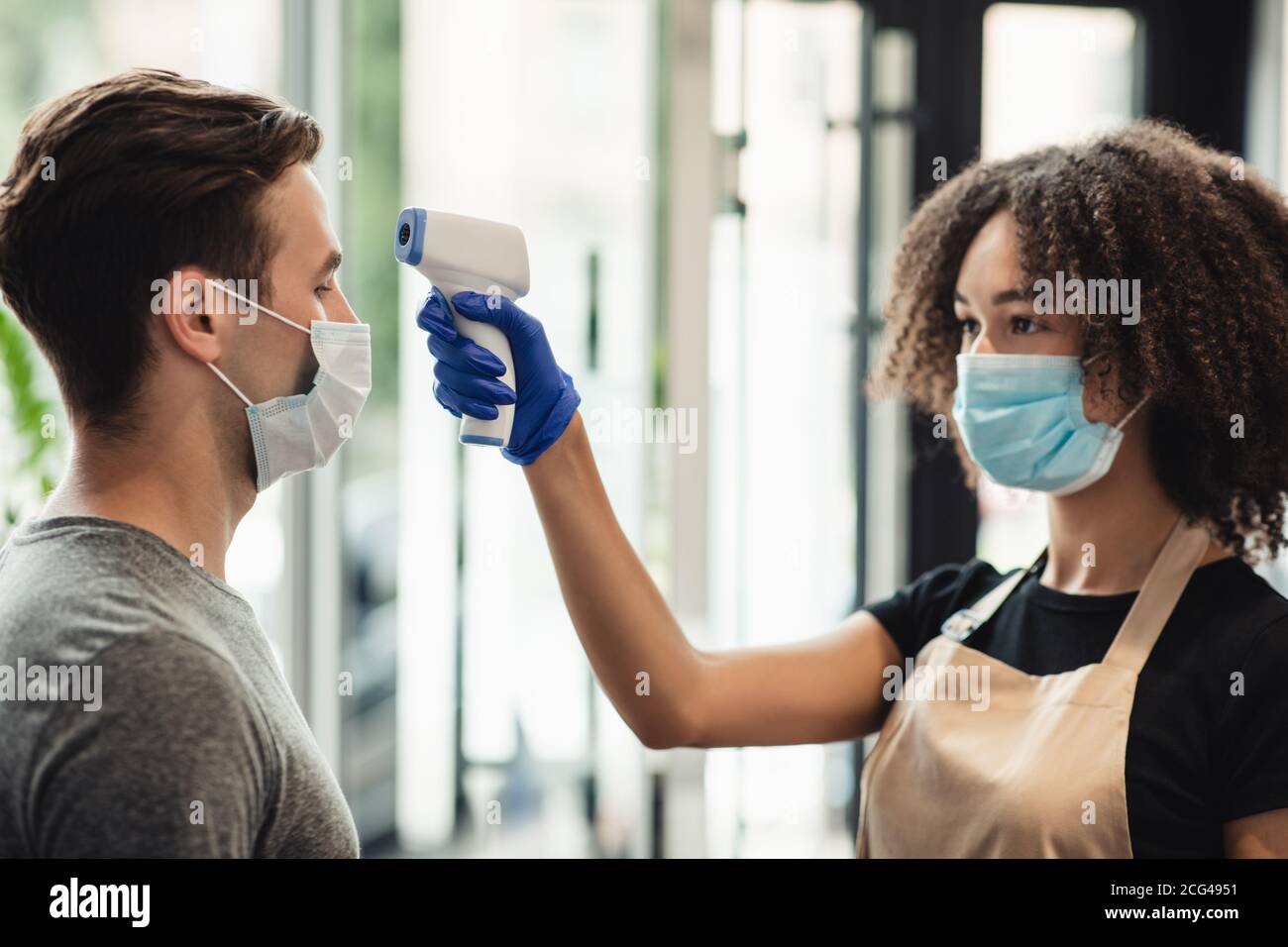 Manager measuring body temperature of client in salon interior Stock ...