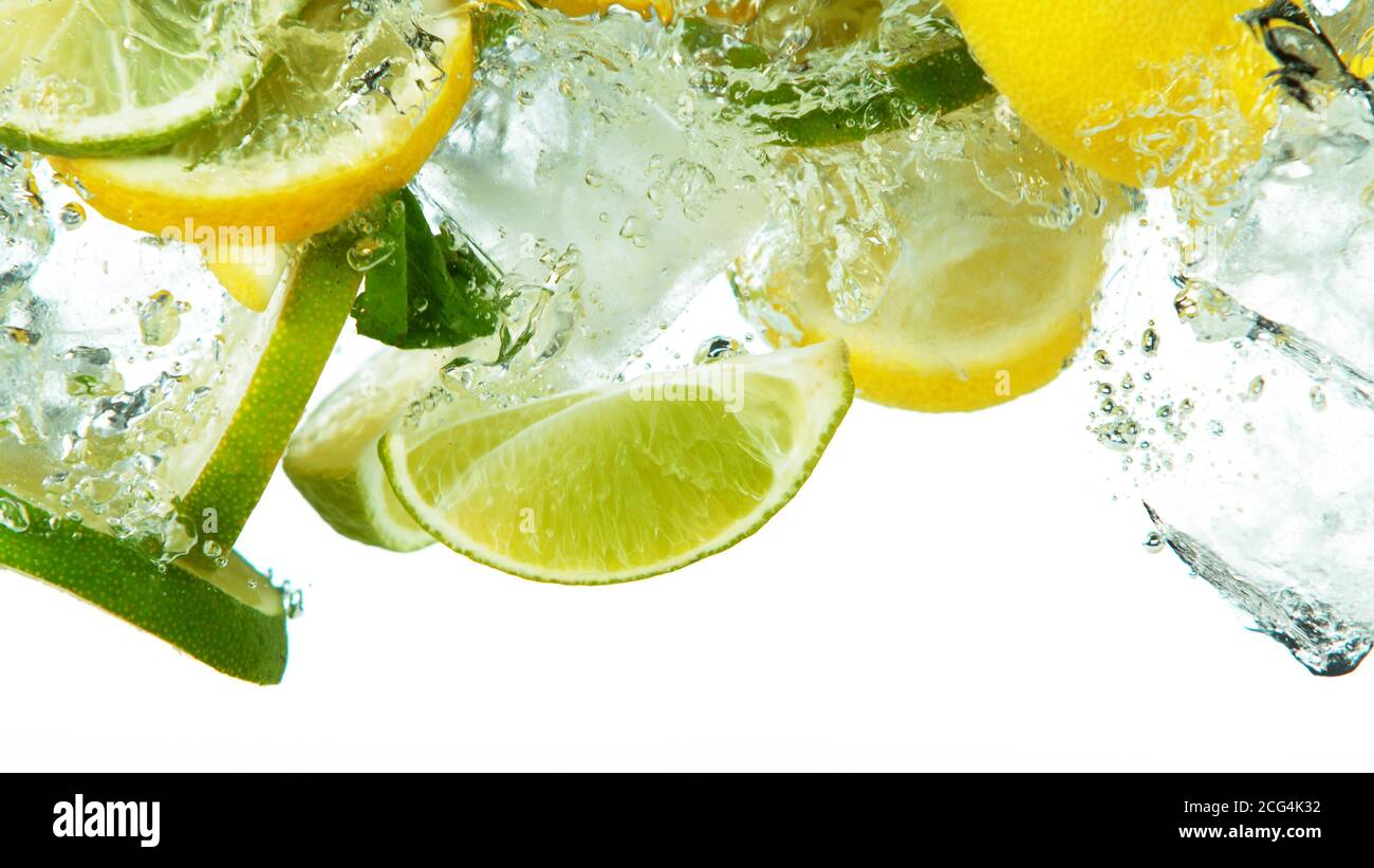 Lemon and lime slices with ice cubes and leaves falling deeply under water isolated on white ...