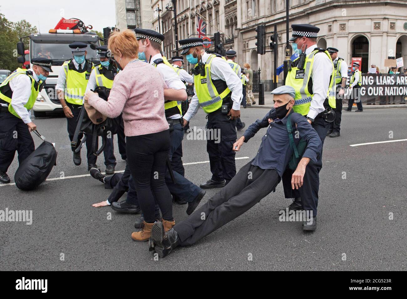 Police officers remove protesters who have sat down in the road by ...
