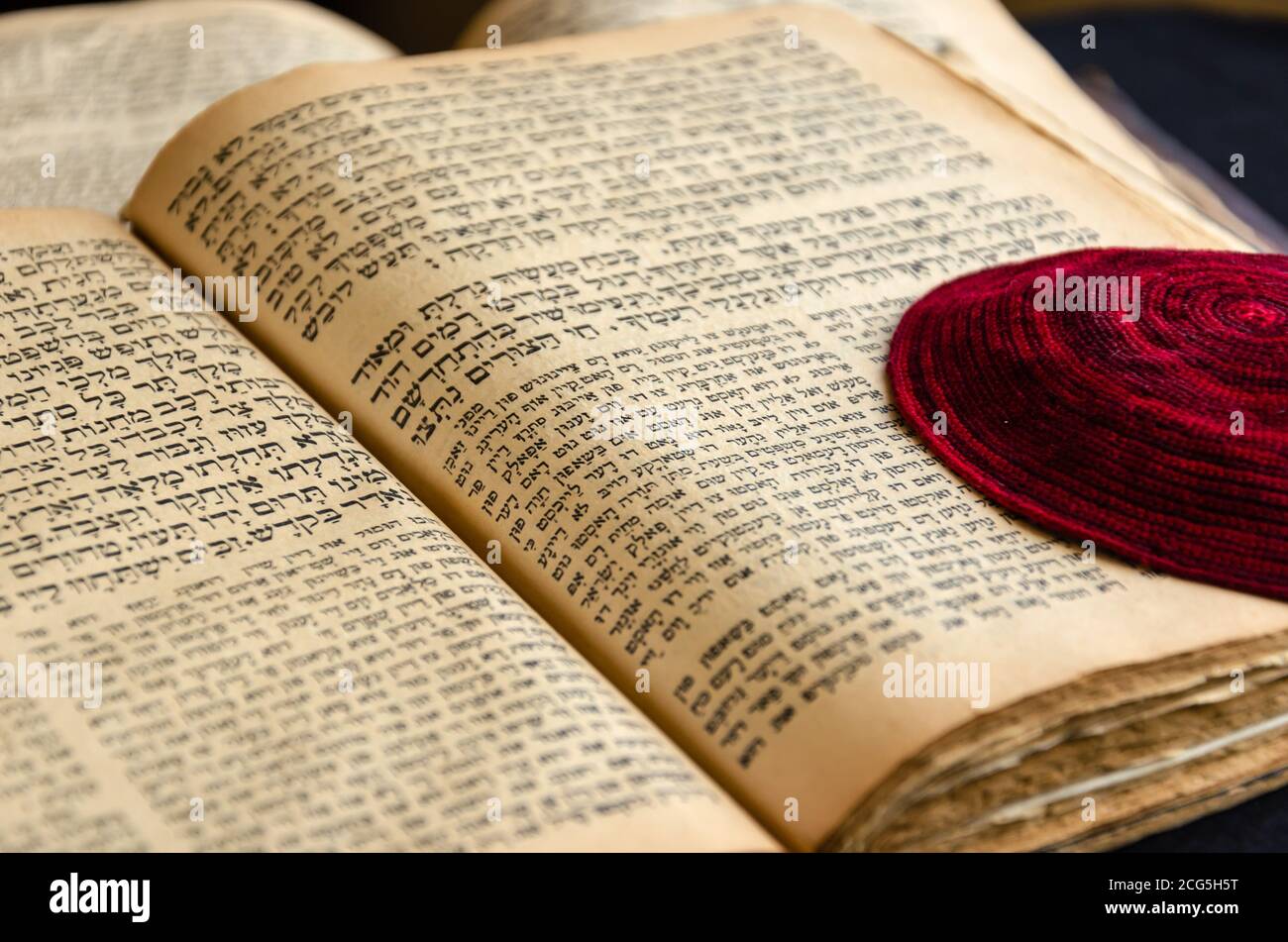An open old Jewish book. Red knitted jewish bale lies on an open ...