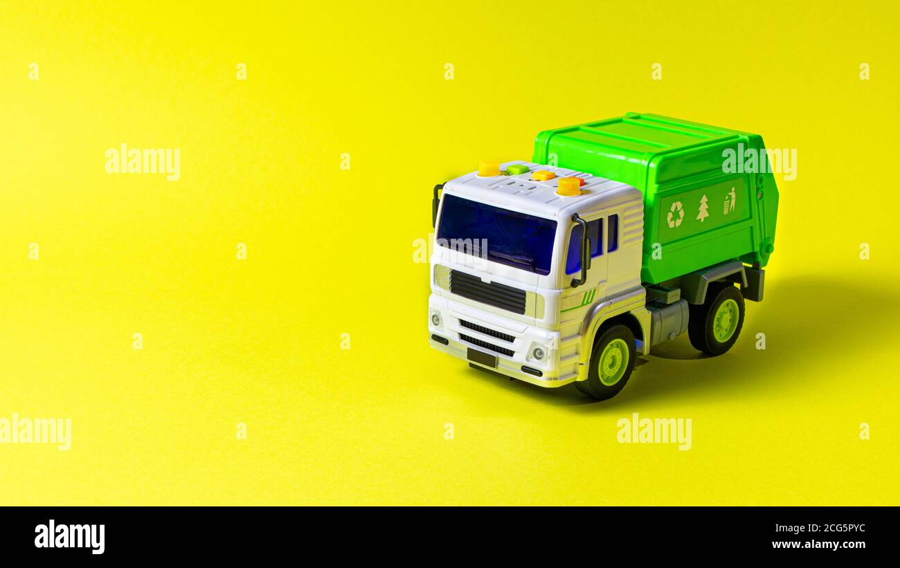 The toy is a garbage truck green with a white body on a yellow ...