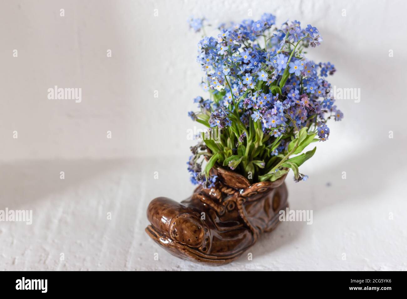 Ceramic slipper with a bouquet of forget-me-nots on a white background ...