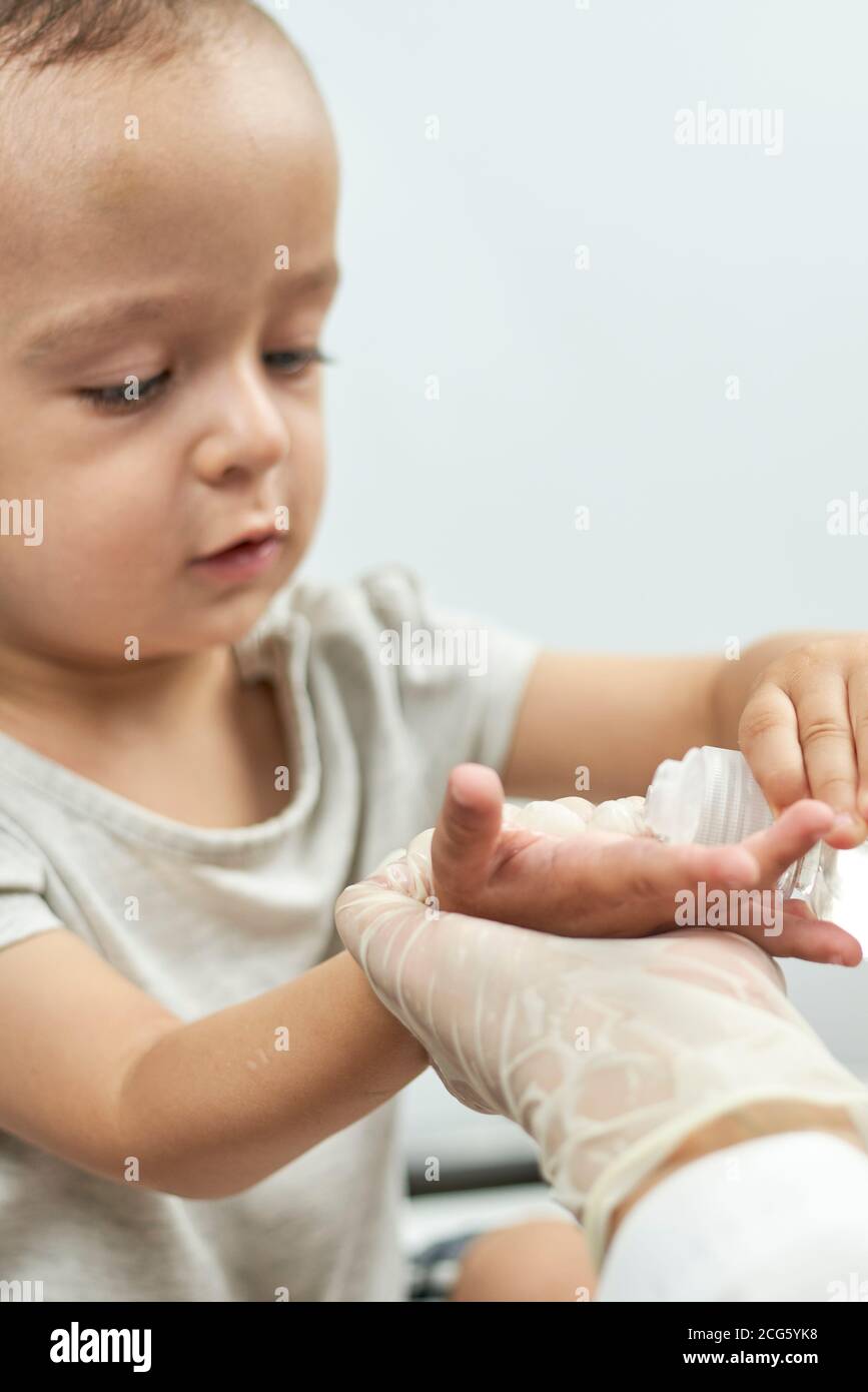 Doctor putting hand sanitizer to baby hands. Teaching a baby boy hand ...
