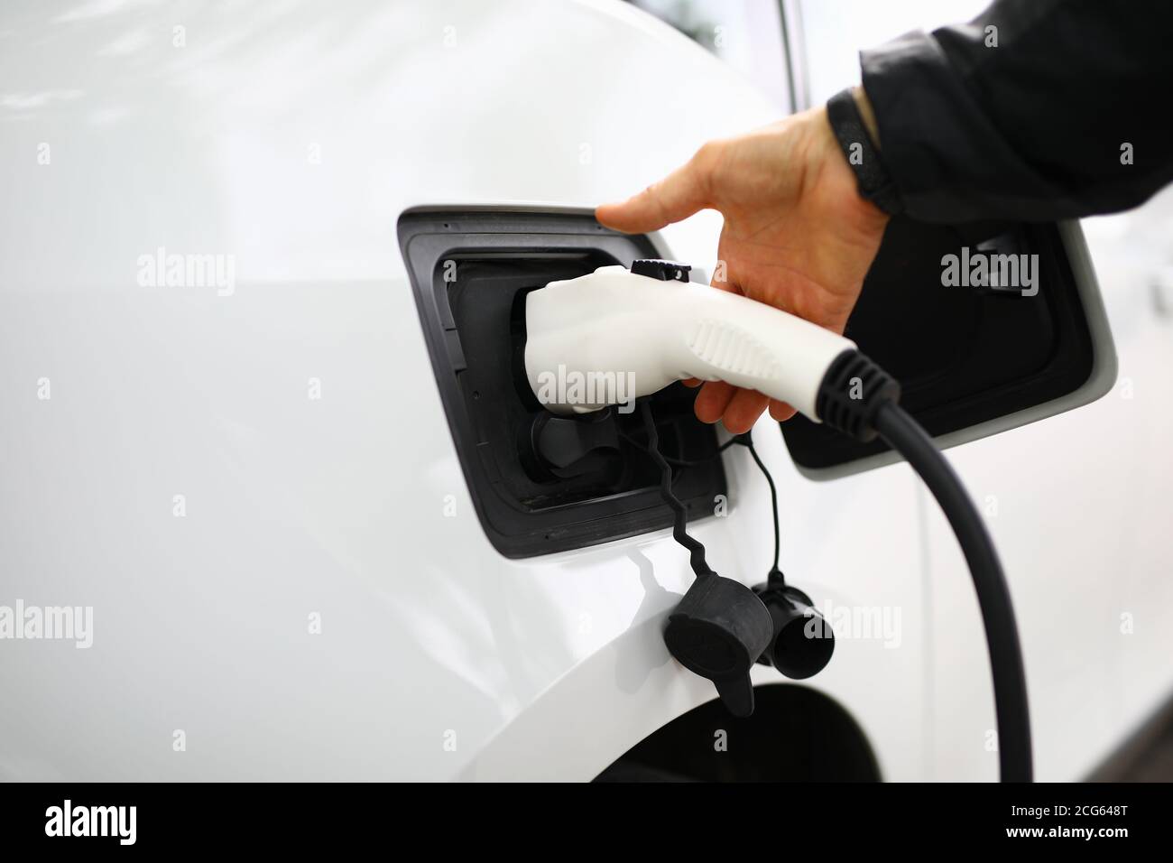 Male hand holds inserts plug for charging into car Stock Photo - Alamy