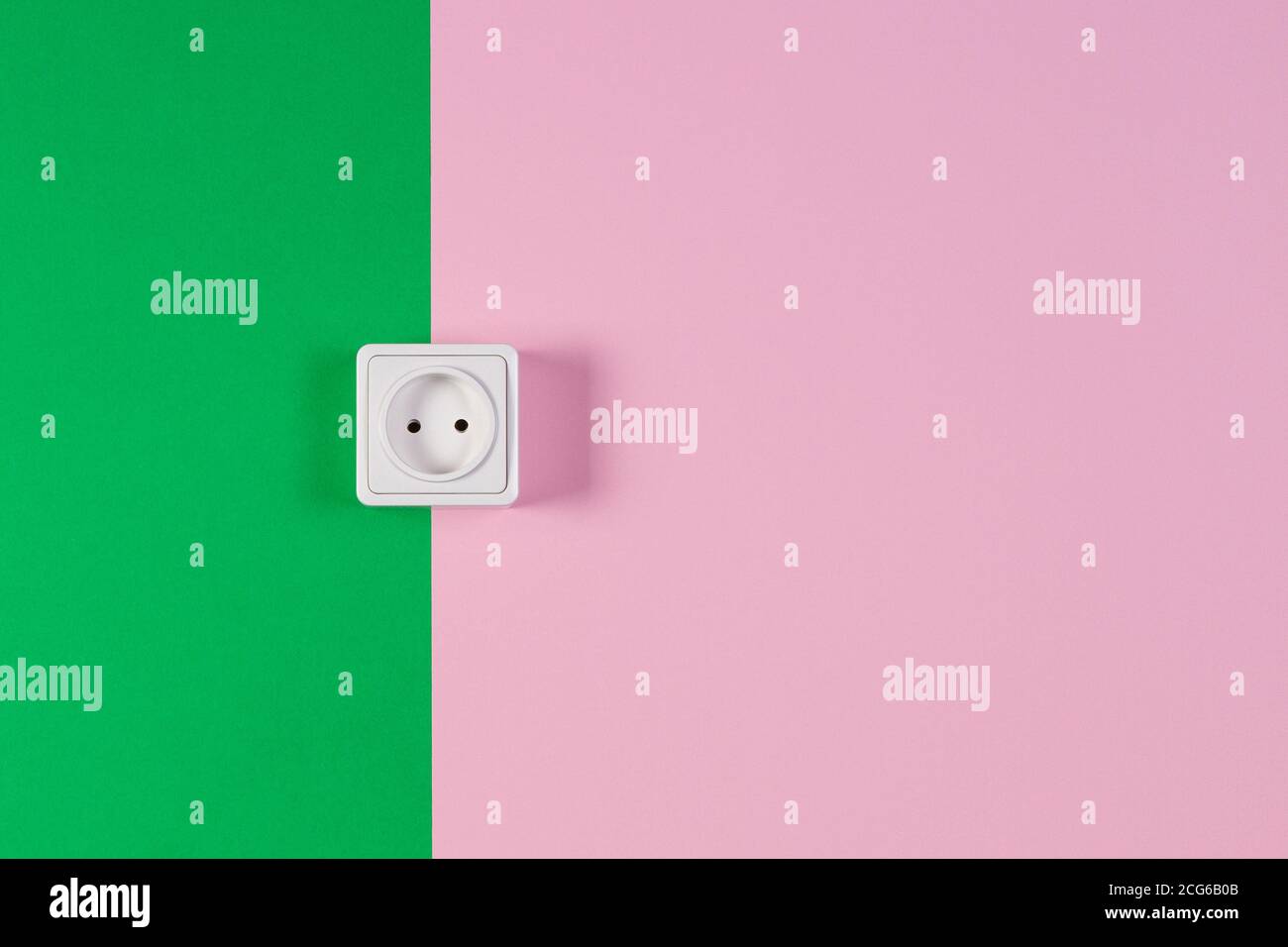 White electrical socket on light pink and green color background Stock ...