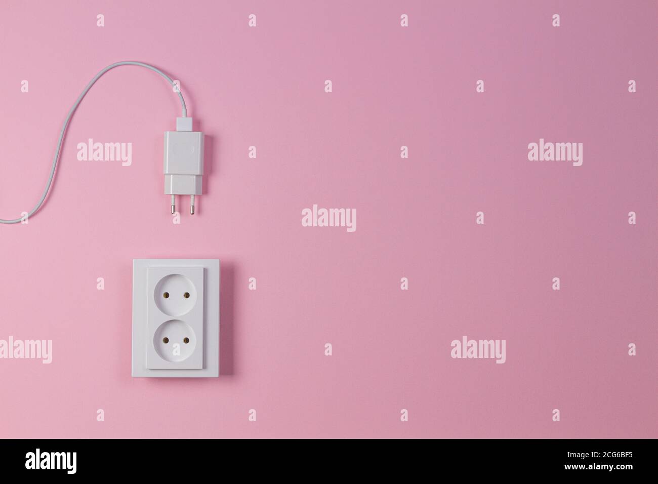 White electrical power socket and power plug on light pink background ...