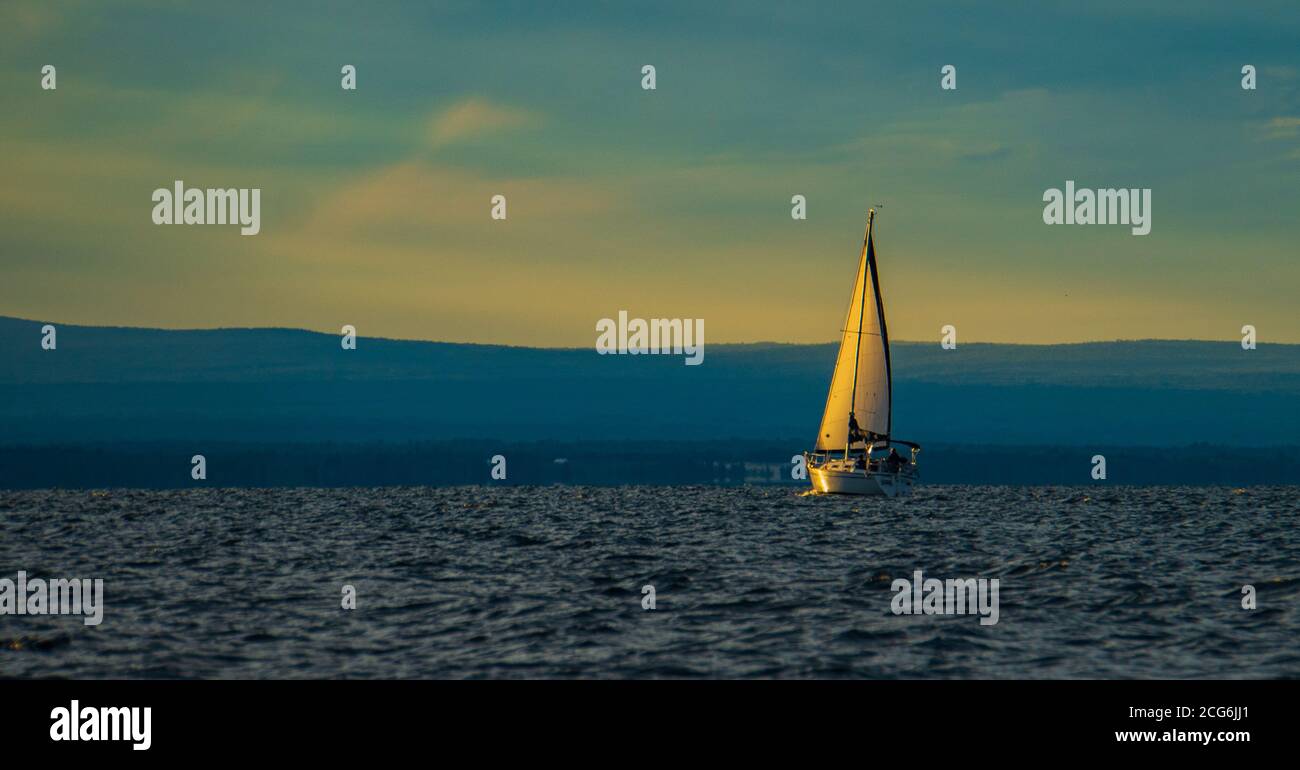 setting sun lights up the sails of sailboat on Lake Champlain ...