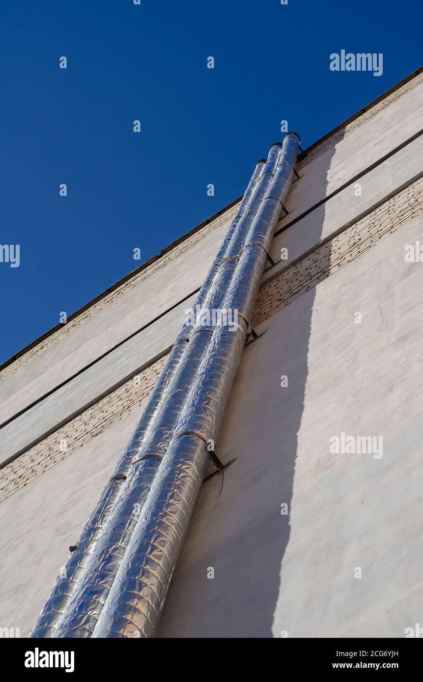 The outer wall of the building with insulated pipes. High brick wall ...