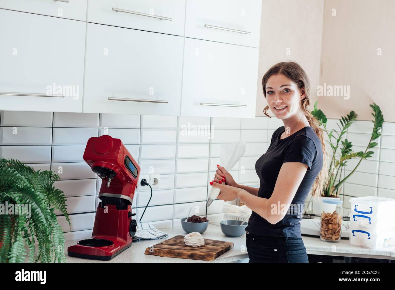 Beautiful woman pastry chef makes sweet cakes in kitchen Stock Photo ...