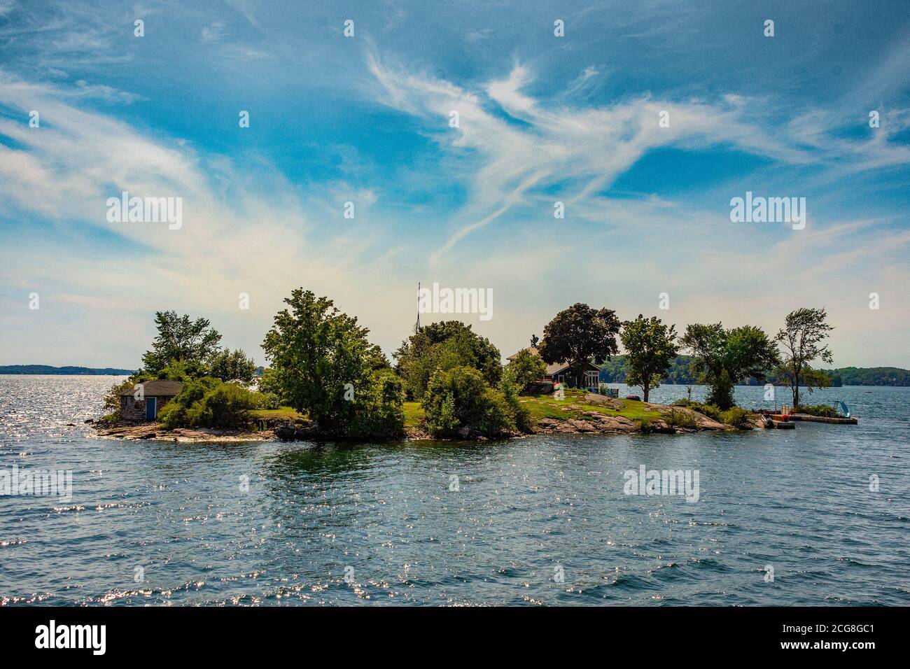 Buildings on an islet in a large lake hidden by large trees and bushes ...