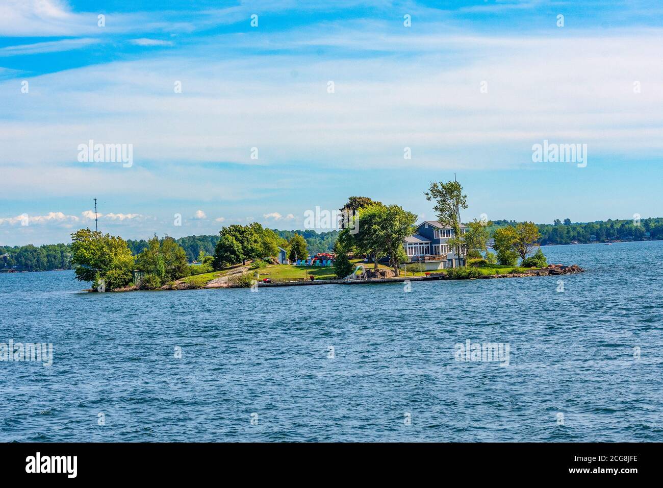 Buildings on an islet in a large lake hidden by large trees and bushes ...