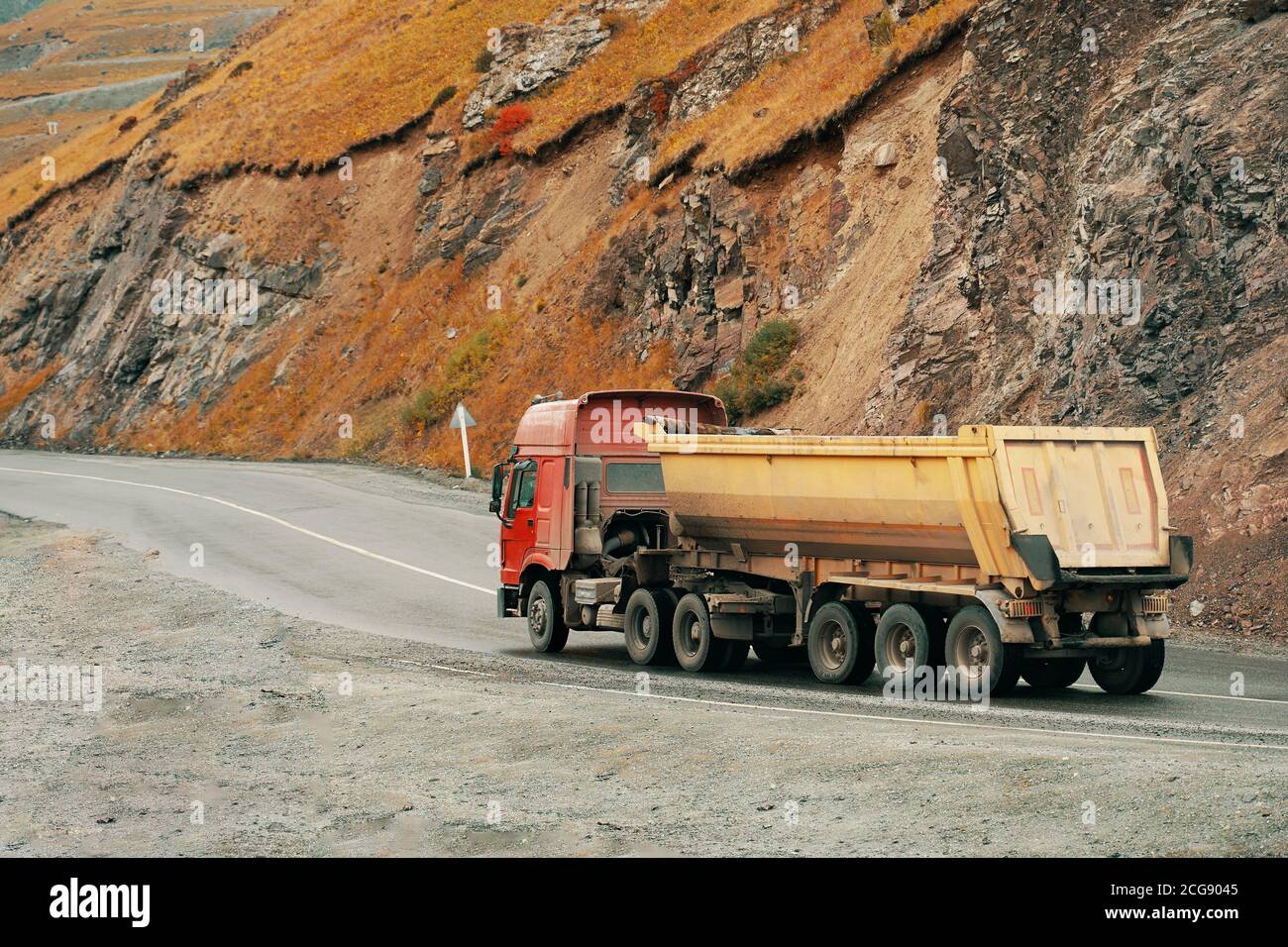 Truck carrying bulk materials moves along a road on the mountains ...
