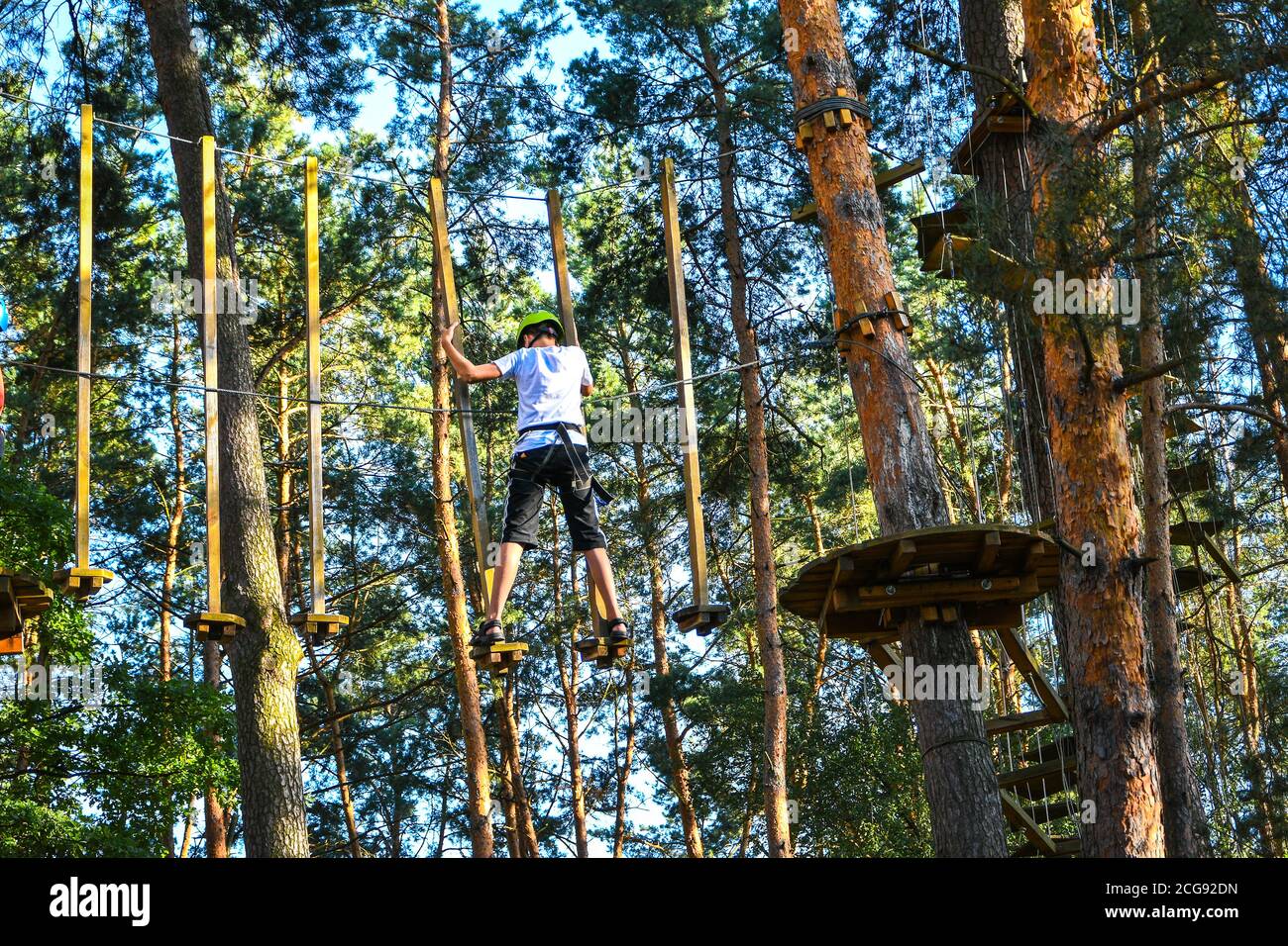 Adventure climbing high wire park. Close-up. Young boy in helmet having ...