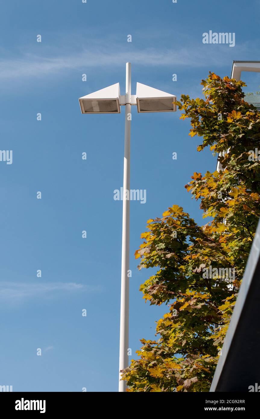 a modern street light in a city painted white with rectangled shaped ...