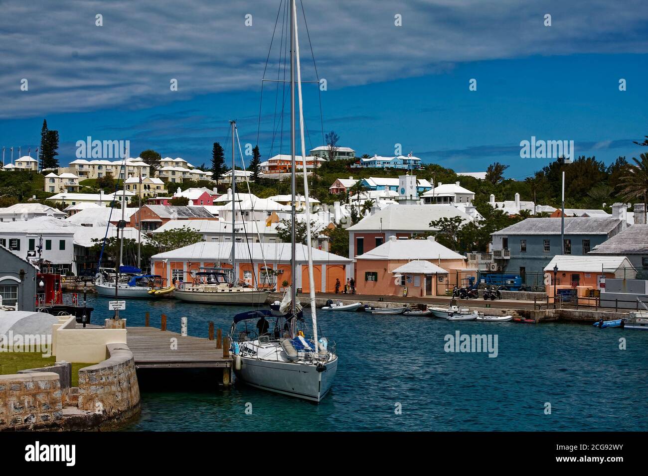 harbor scene; sailboats docked; dinghies; pastel houses; water; town ...