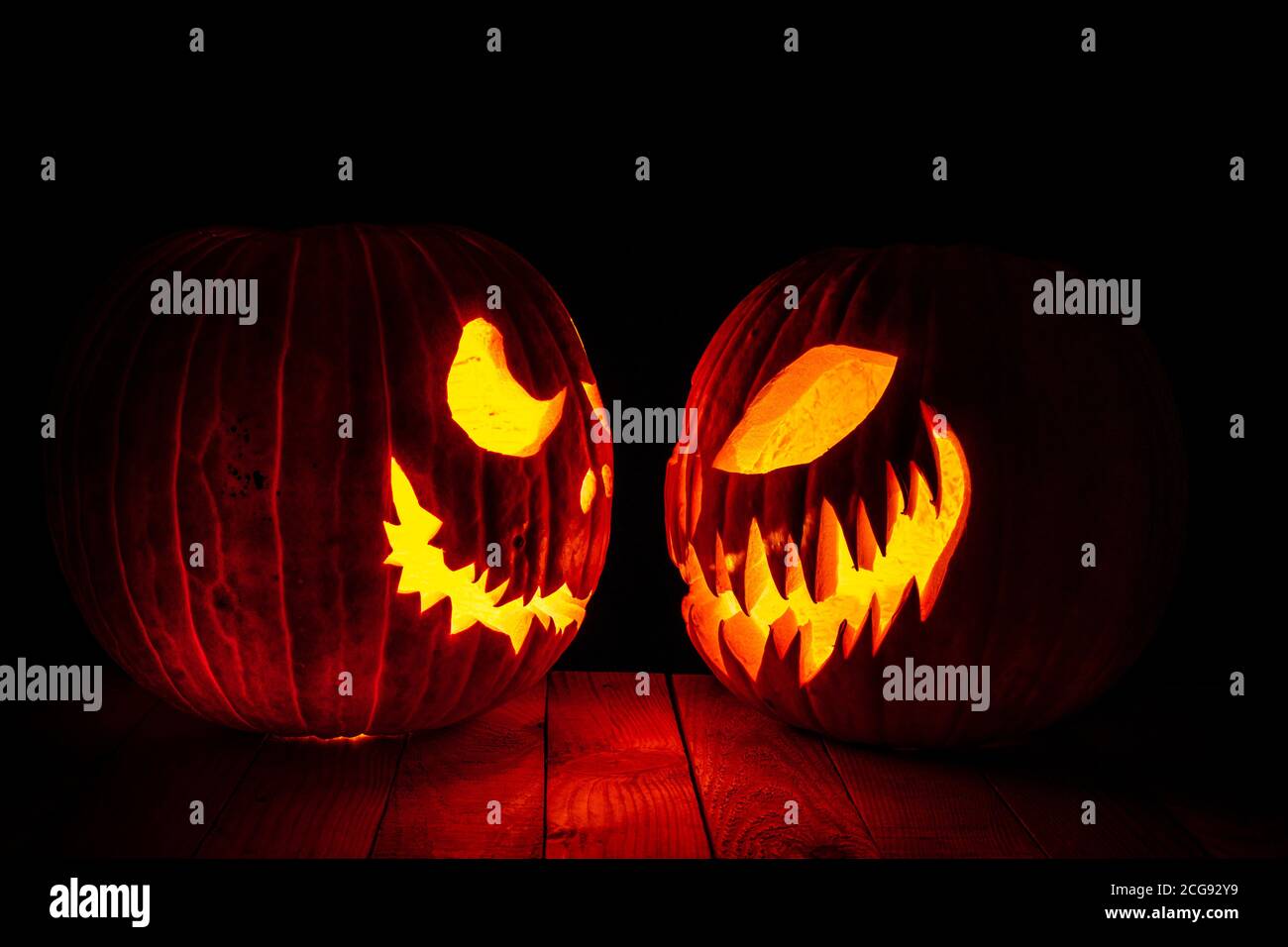 carved halloween pumpkins looking at each other, side view. wooden base ...