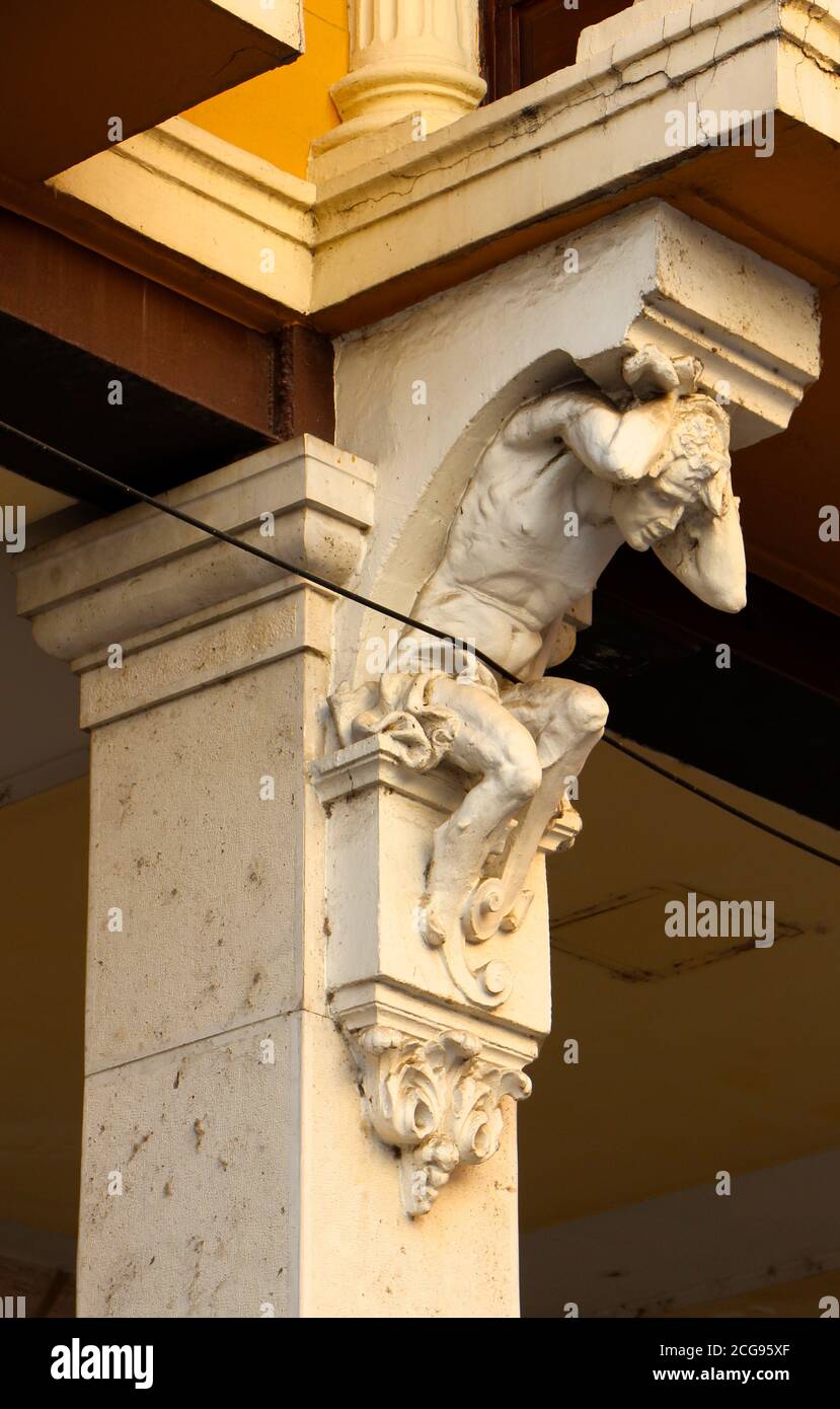 Sculpture in stone at the top of the column of a bent man holding up ...