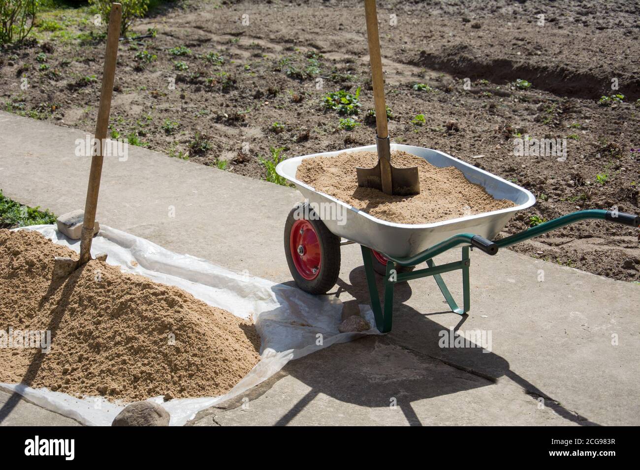 Garden metal wheelbarrow cart with sand and shovel on construction site ...