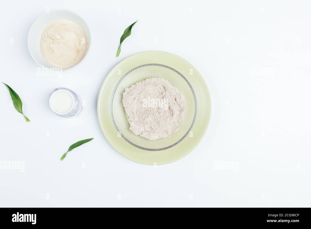 Natural homemade cosmetics, moisturizer cream and green leaves on white ...