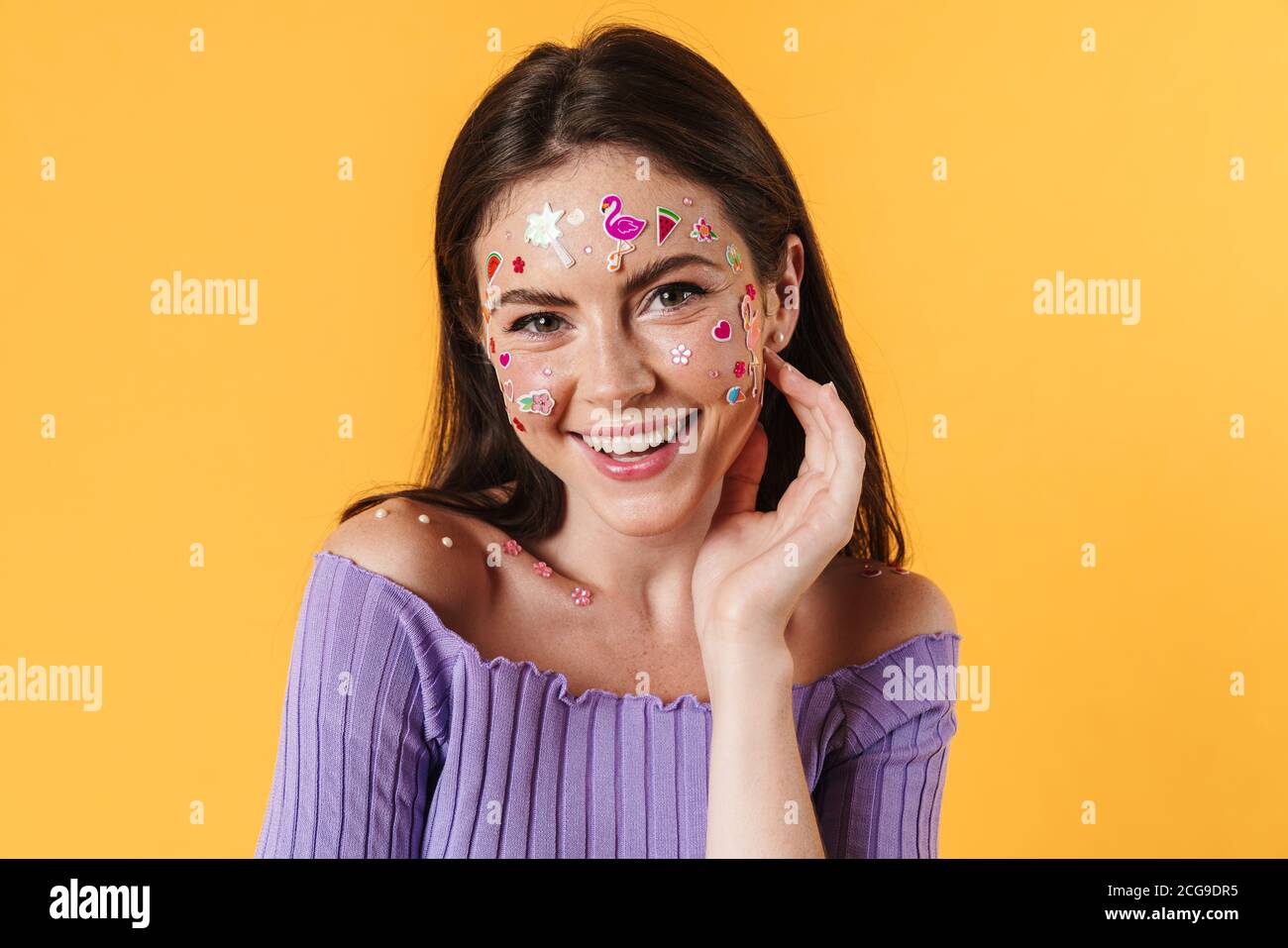 Image of young cheerful woman with stickers on face smiling at camera ...