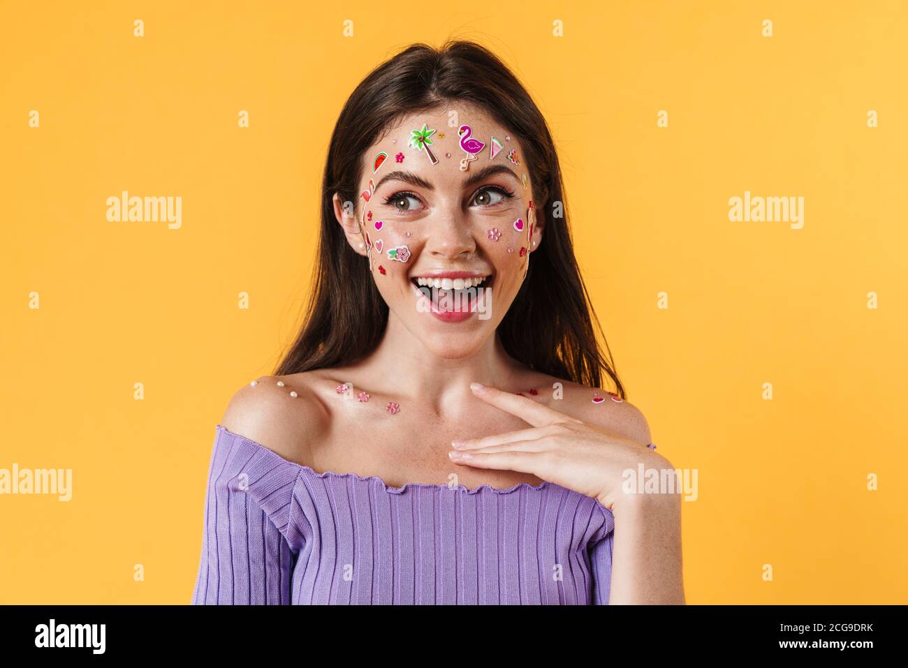 Image of young excited woman with stickers on face smiling at camera ...