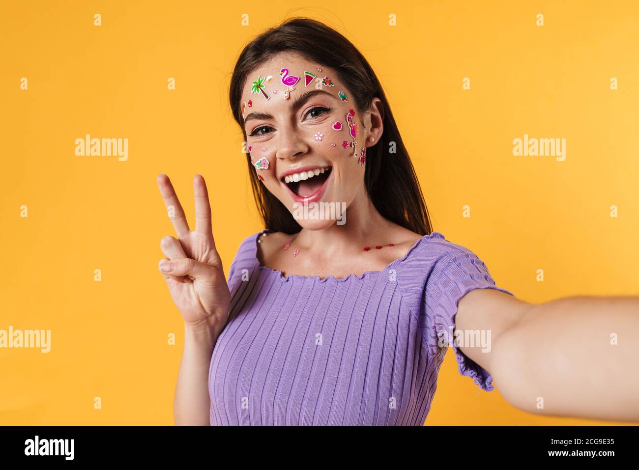 Image of happy woman with stickers on face gesturing peace sign while ...