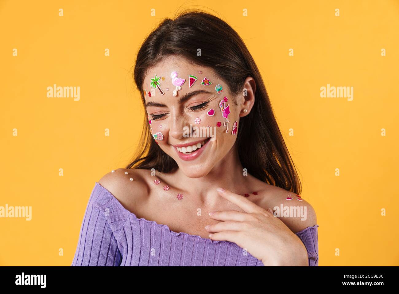 Image of young joyful woman with stickers on face laughing at camera ...