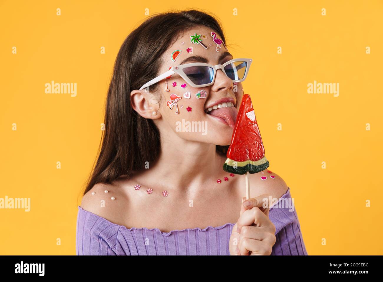 Image of young funny woman with stickers on face liking lollipop and ...