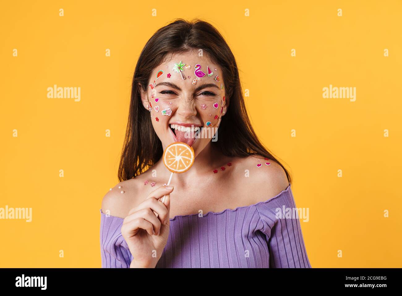 Image of young funny woman with stickers on face liking lollipop and ...