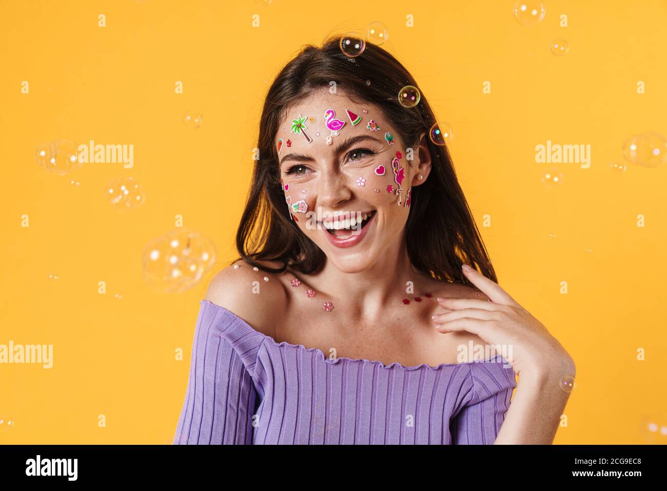 Image of young excited woman with stickers on face laughing at camera ...