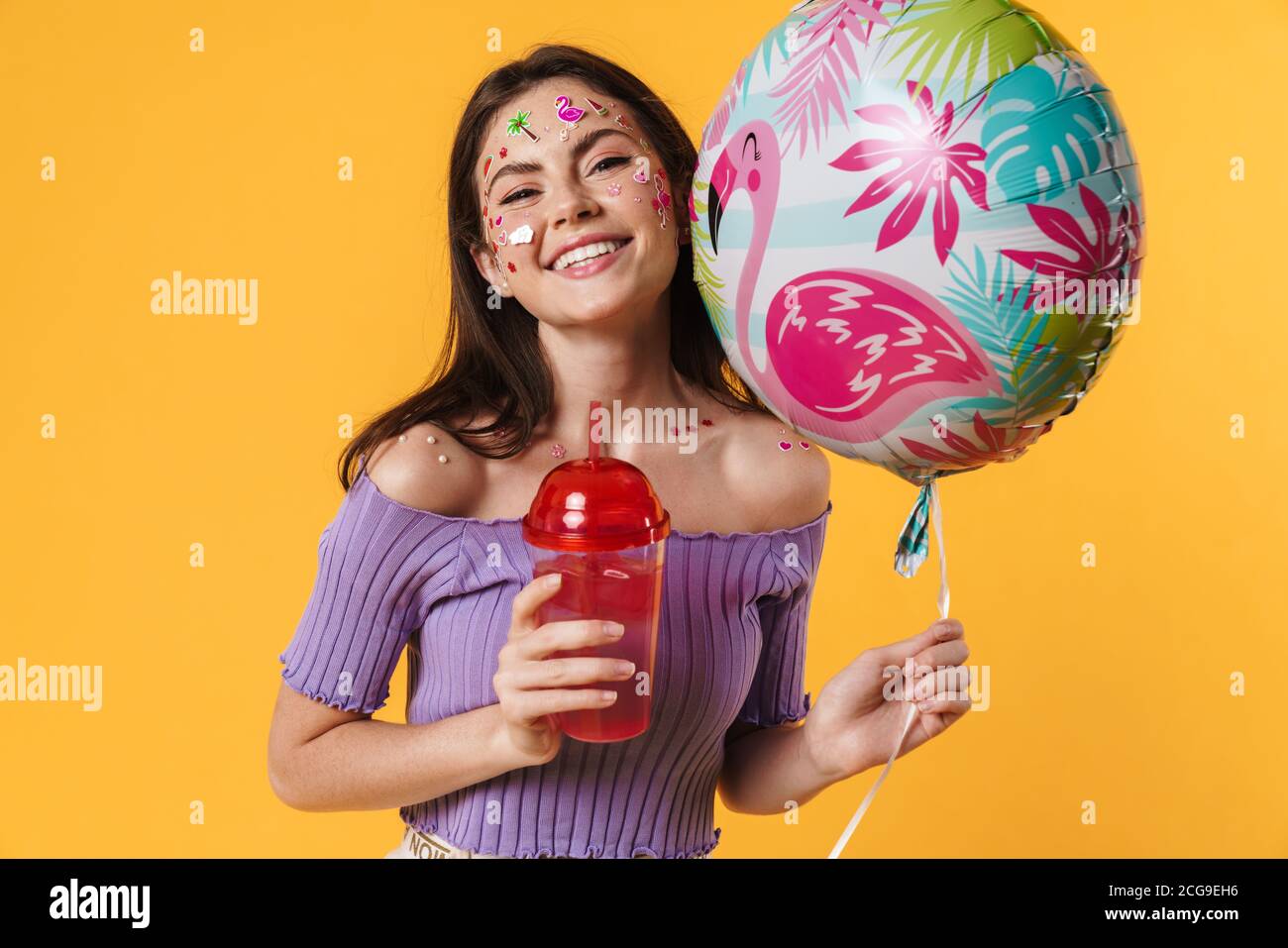 Image of laughing woman with stickers on face holding balloon and ...