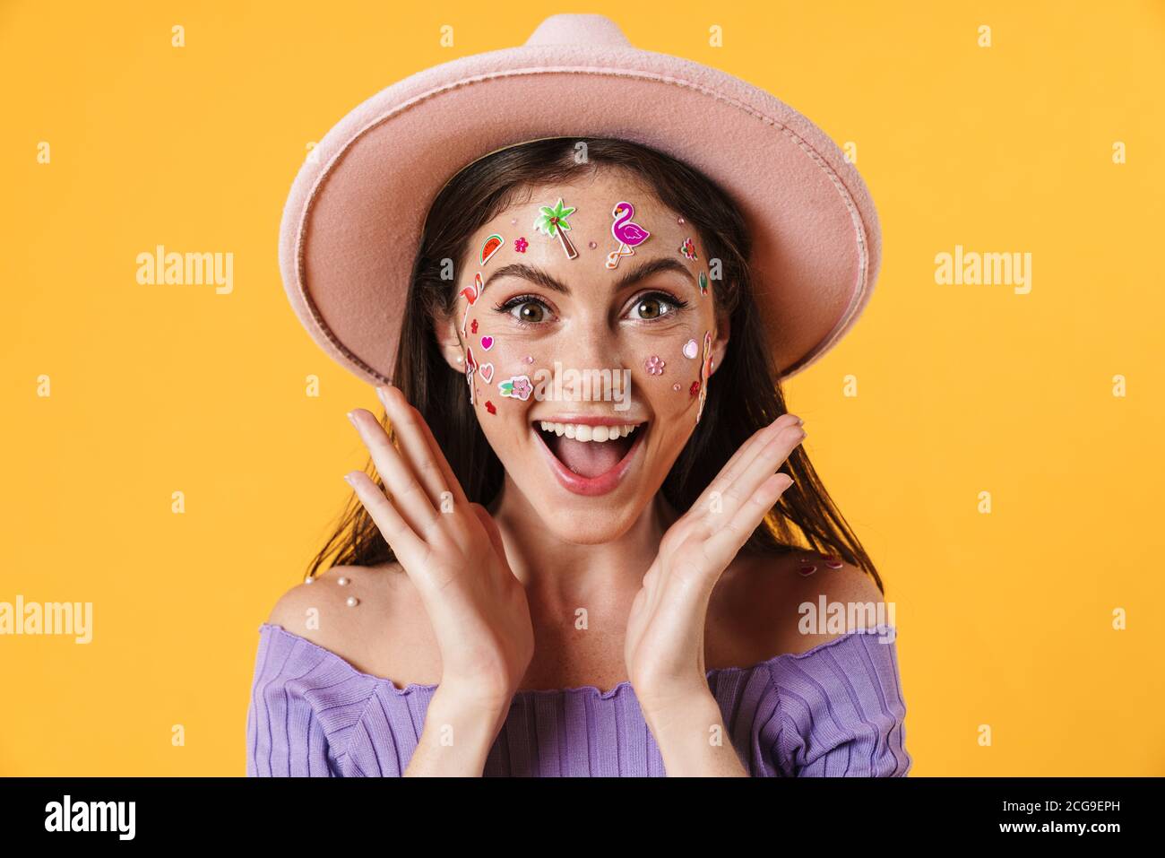 Image of young excited woman with stickers on face posing in pink hat ...